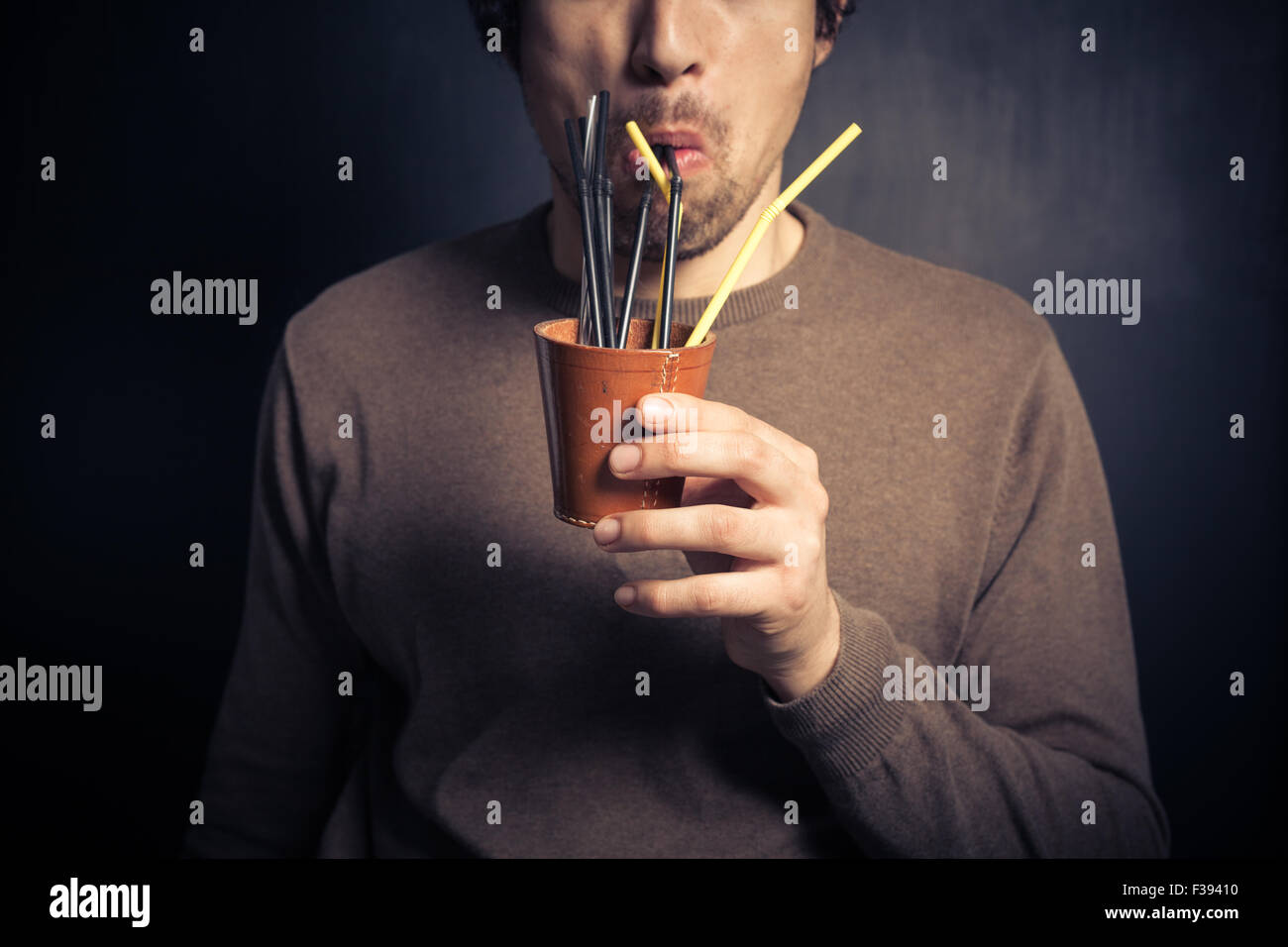 A silly young man is drinking from a leather cup with a bunch of ...