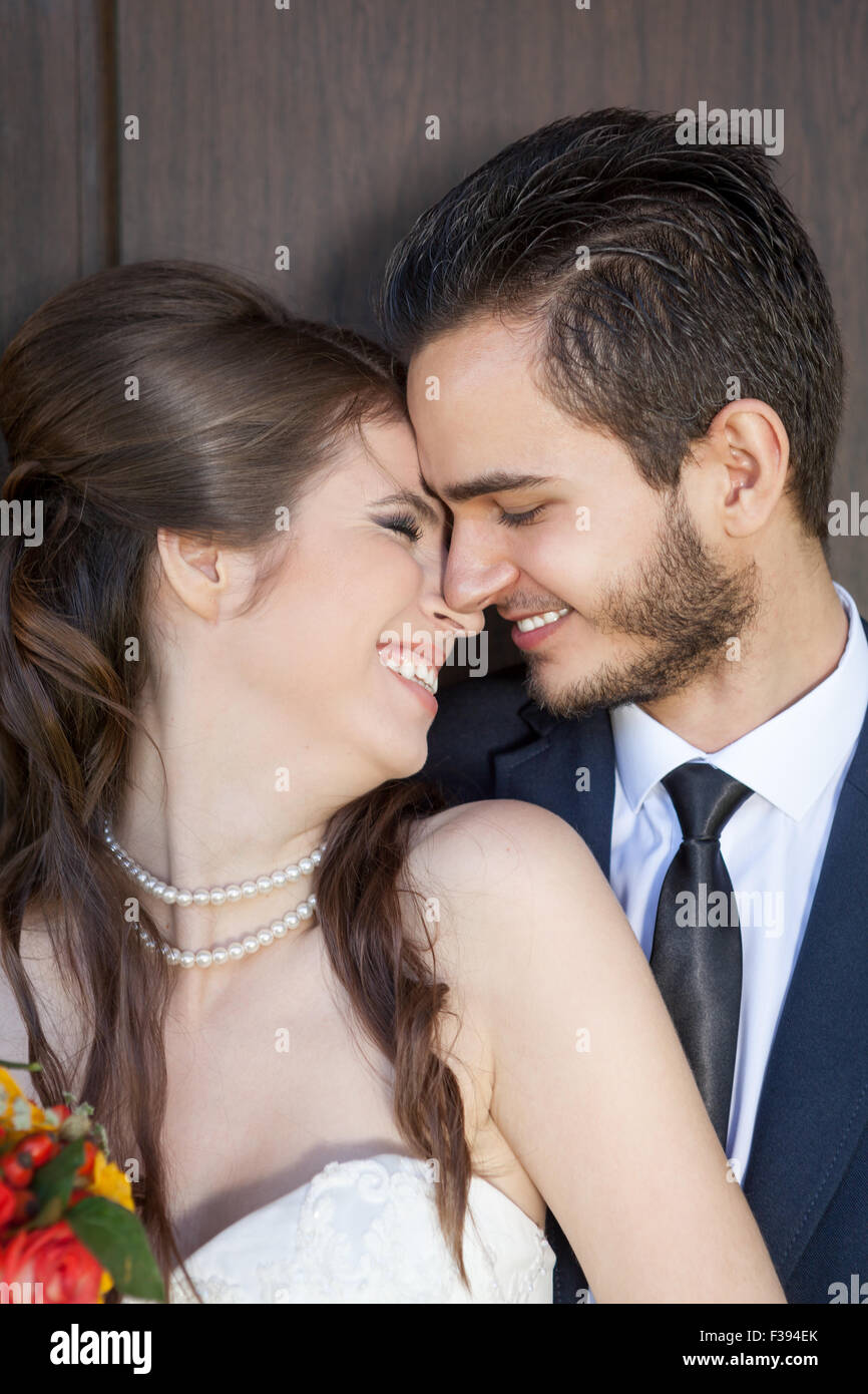 Laughing young bride and happy groom looking at her on wooden ...