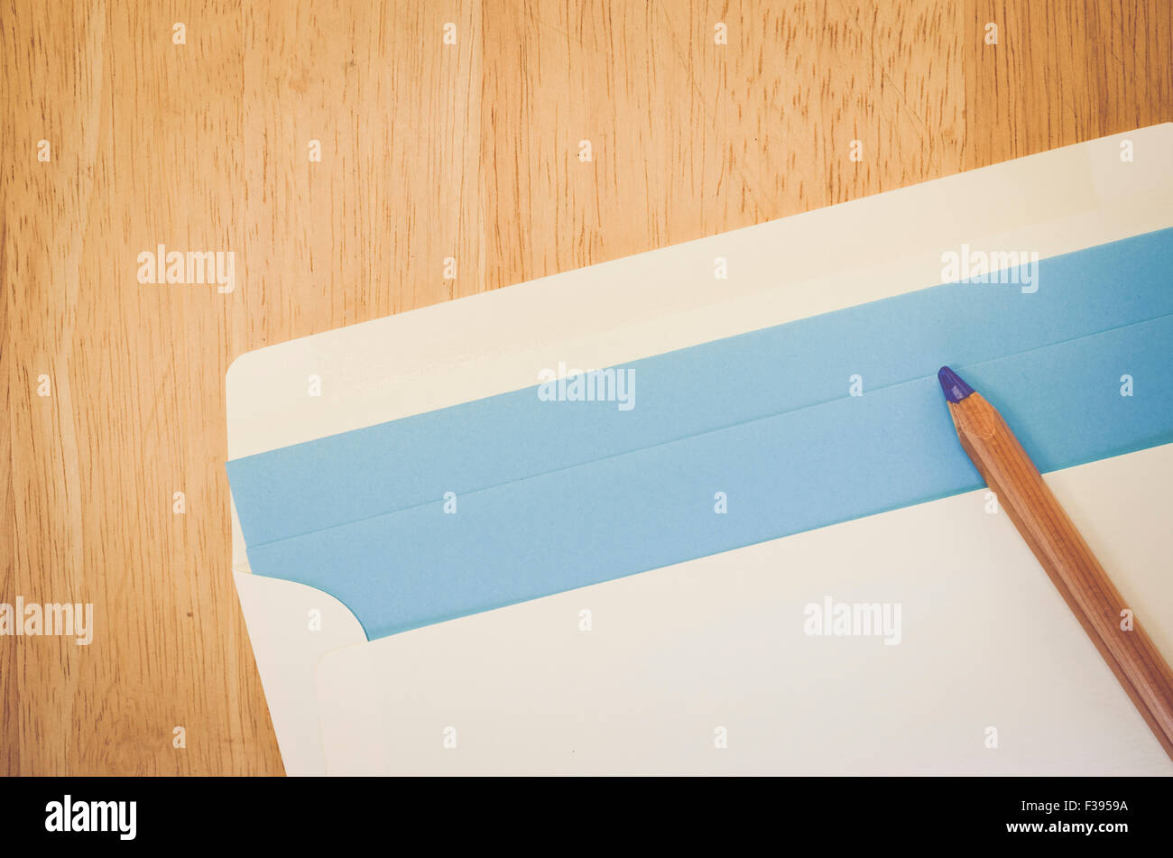 white envelope pencil and blue writing paper on a natural wood surface ...