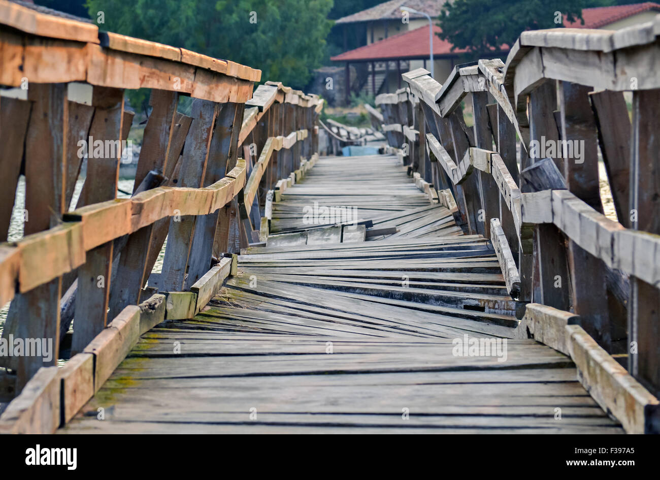 Closeup of a deformed and dilapidated wooden bridge over the river ...