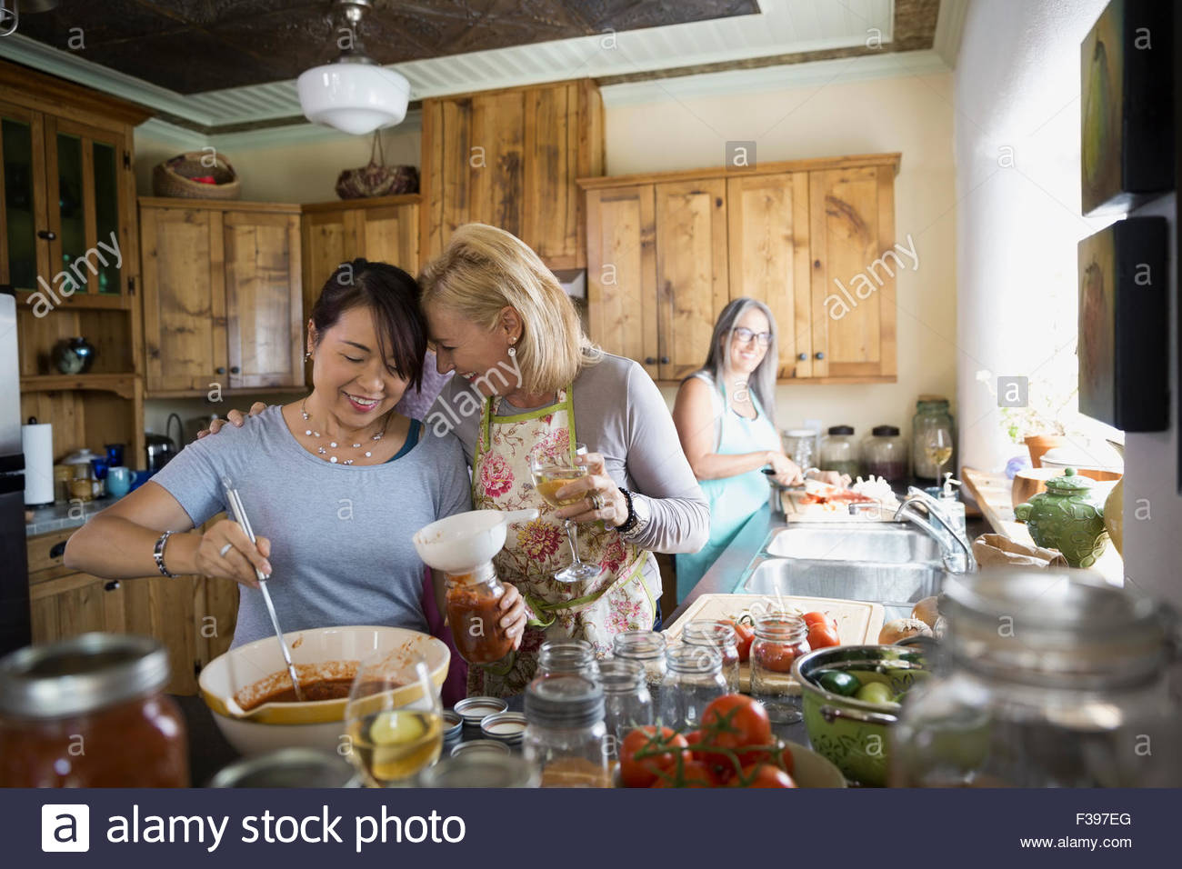 Smiling women canning tomato sauce in kitchen Stock Photo - Alamy