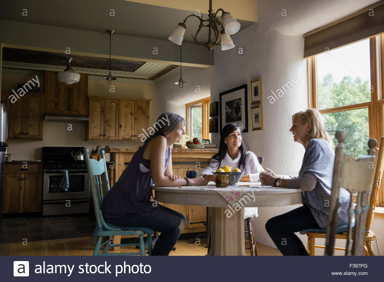 Women talking and drinking coffee at dining table Stock Photo - Alamy