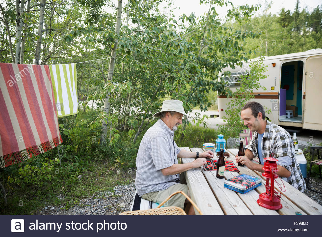 Father and son drinking beer playing checkers campsite Stock Photo - Alamy