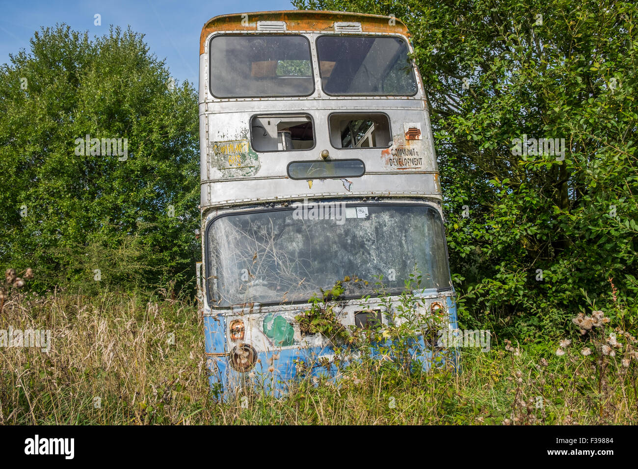 A double decker bus left to rot in a farmers field amongst the trees ...