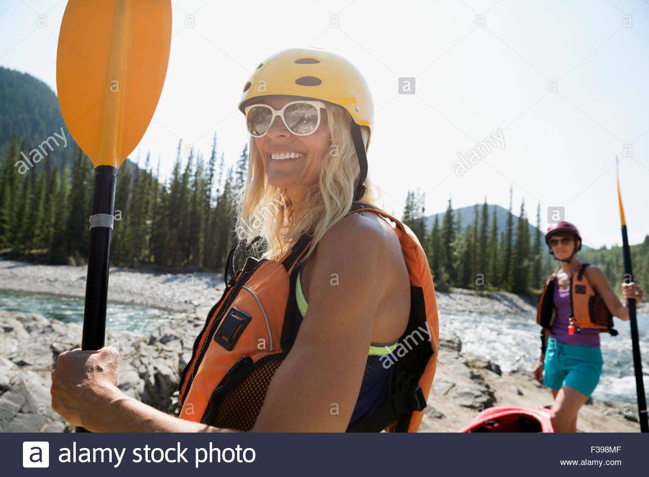 Smiling women with kayak paddles at riverside Stock Photo - Alamy