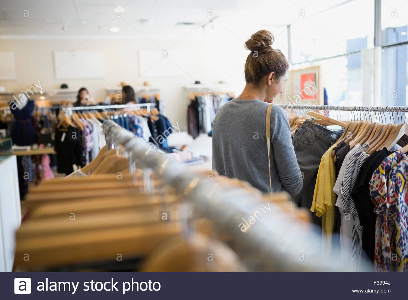 Woman browsing clothing rack in shop Stock Photo - Alamy