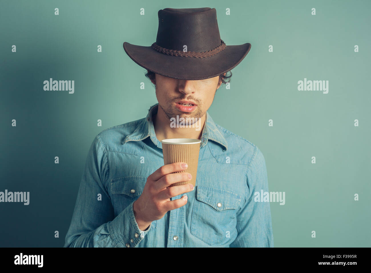 Young cowboy is drinking coffee from a paper cup Stock Photo - Alamy