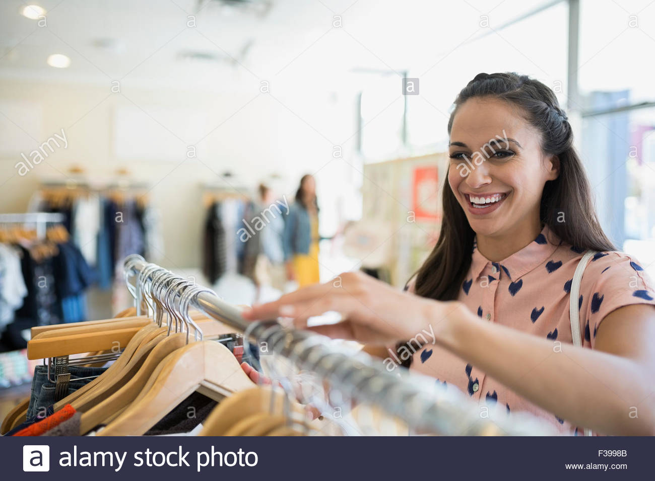 Smiling woman browsing clothing rack in shop Stock Photo - Alamy