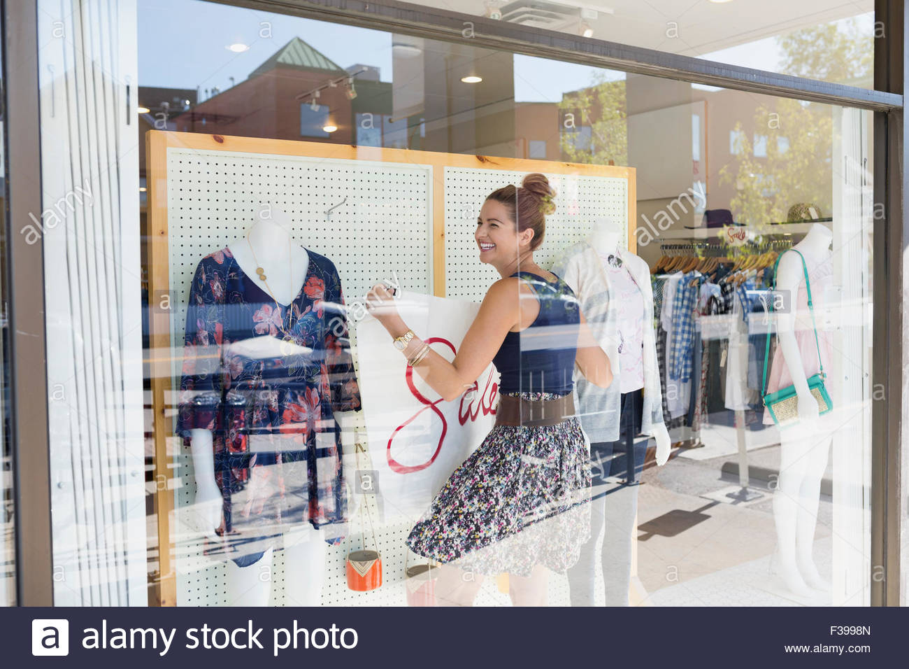 Smiling worker hanging sale sign clothing shop window Stock Photo - Alamy