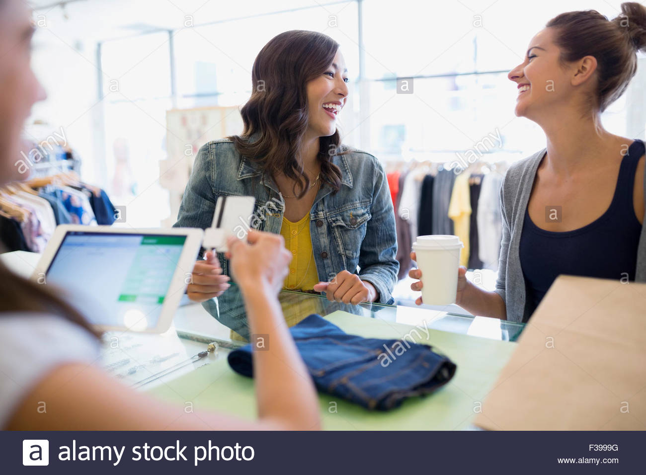 Laughing women paying at shop counter Stock Photo - Alamy