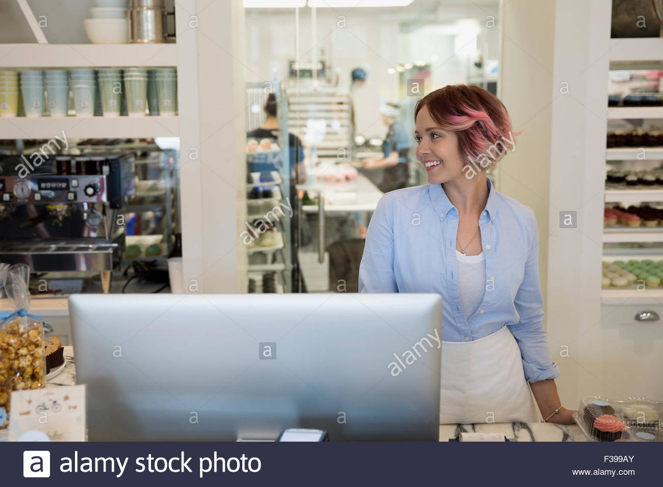Smiling bakery worker looking away behind counter Stock Photo - Alamy