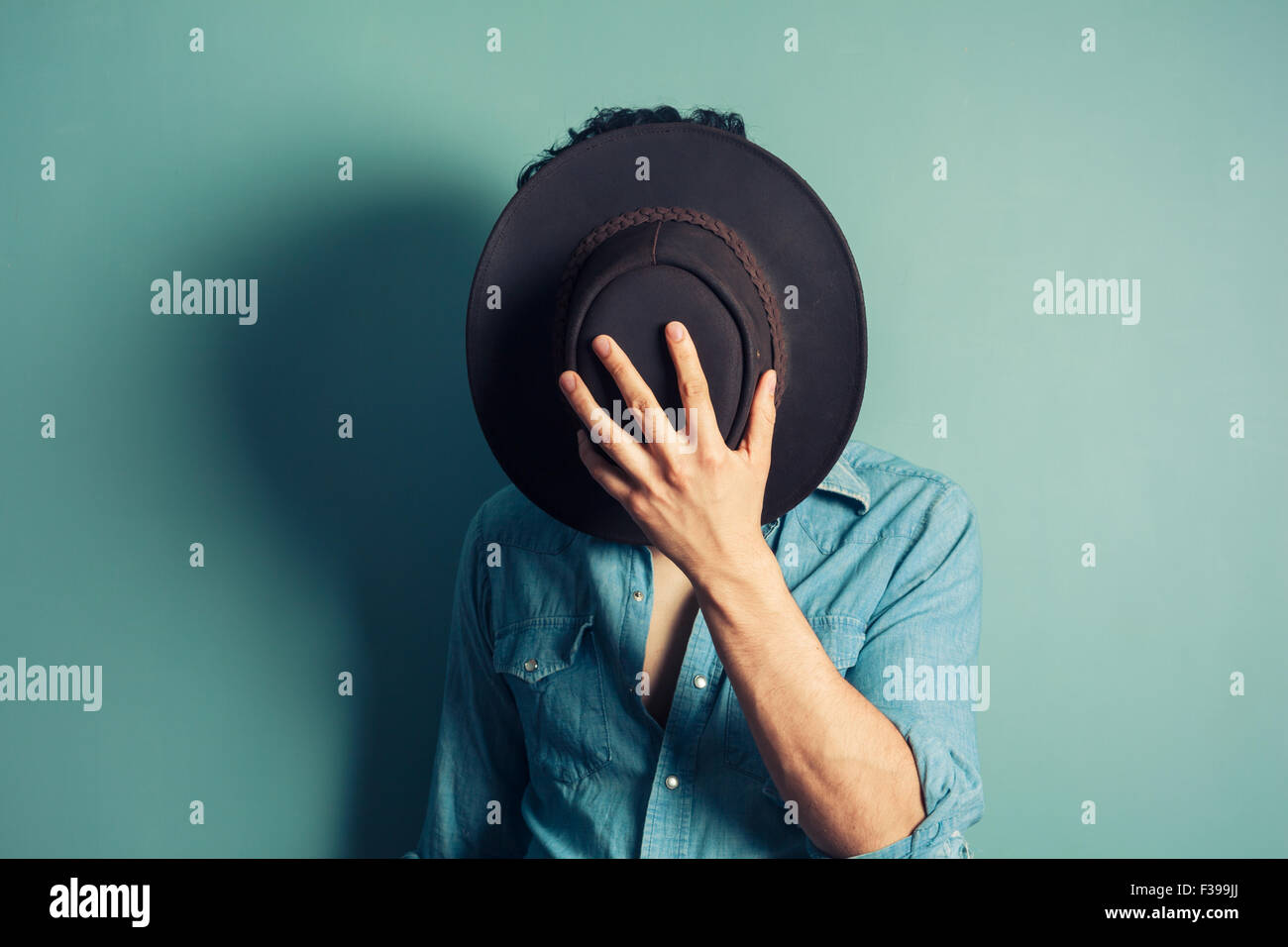 A cowboy is hiding behind his hat Stock Photo - Alamy