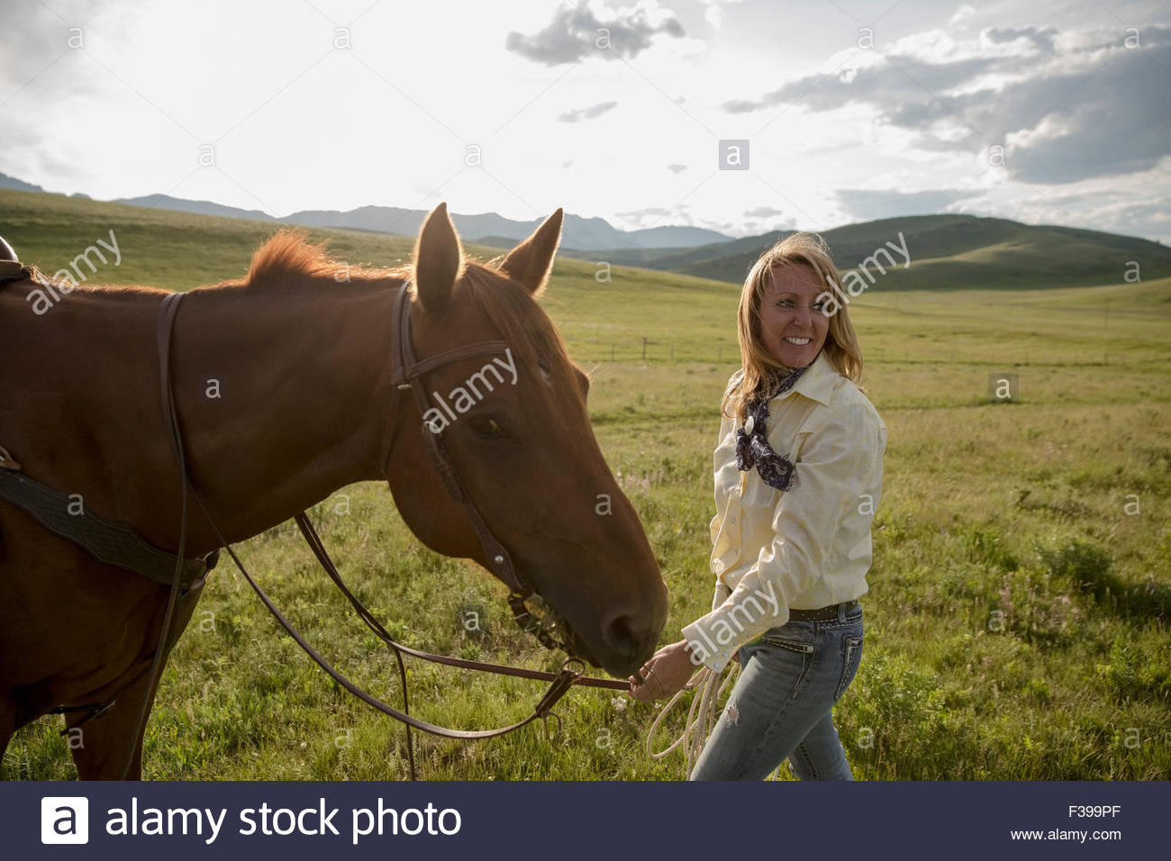 Smiling female rancher with horse in remote field Stock Photo - Alamy