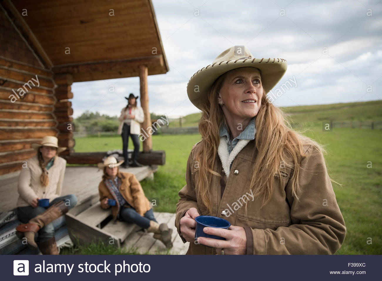 Confident female ranchers drinking coffee cabin porch Stock Photo - Alamy