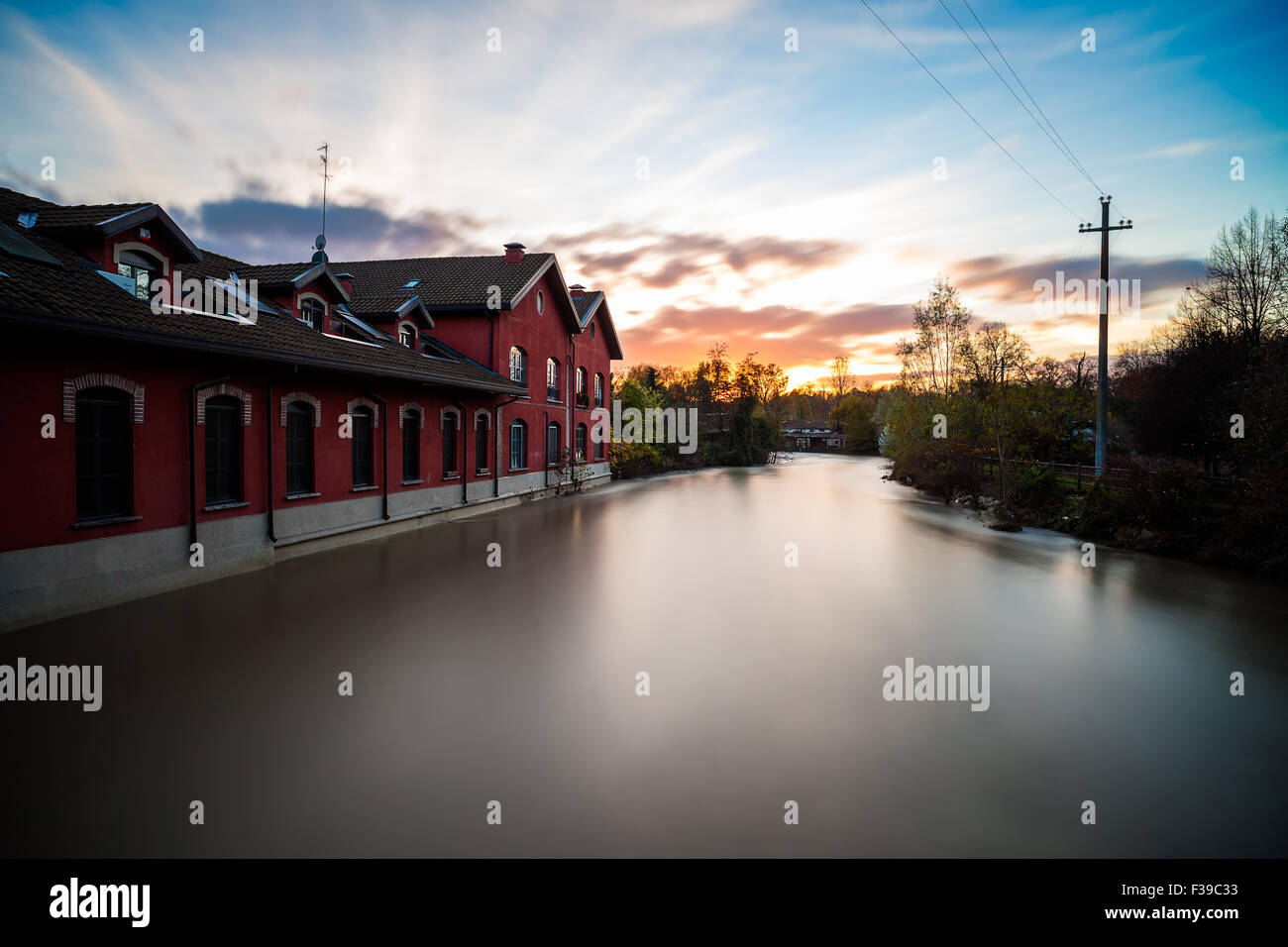 The calm river Lambro in Monza flows along an elegant red building ...