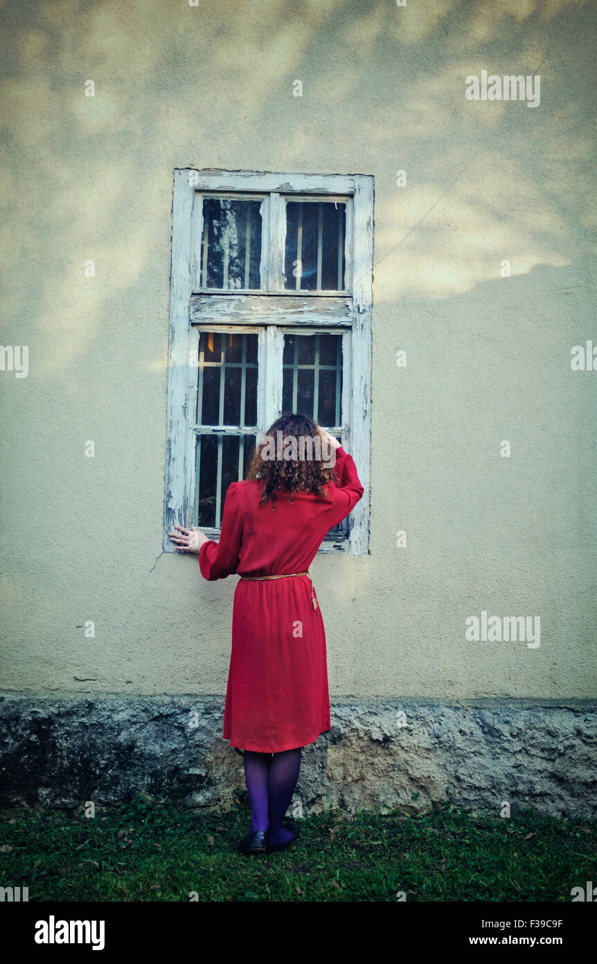 Woman standing outside the house looking through window Stock Photo - Alamy