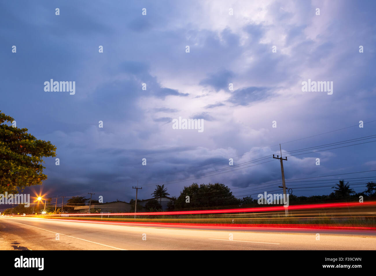 dark cloudy with lightning and light rays in the foreground of the road ...