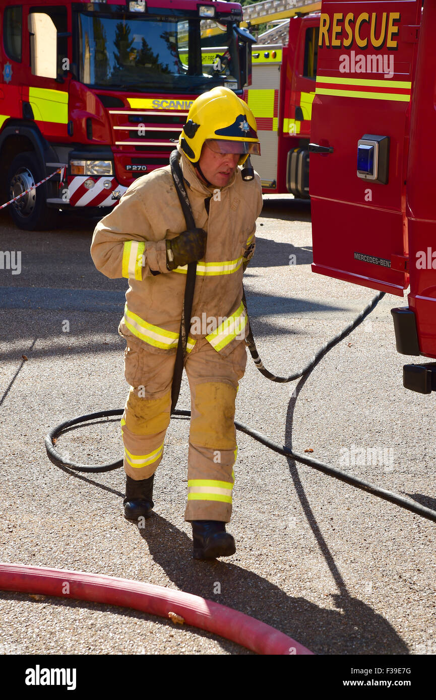 A firefighter runs out a narrow gauge hose at the scene of a fire Stock ...