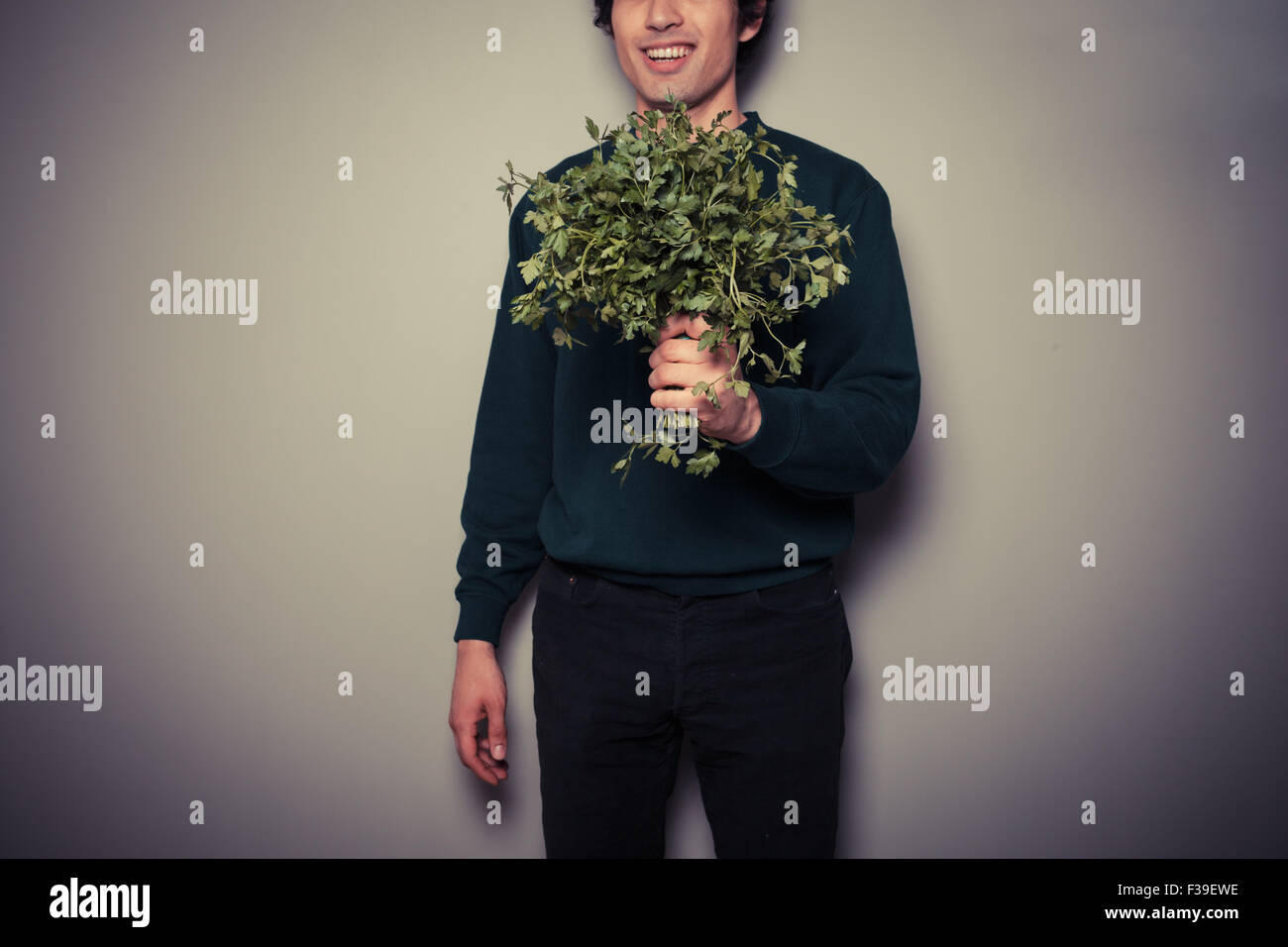 A happy young man is holding a big bunch of fresh parsley Stock Photo ...