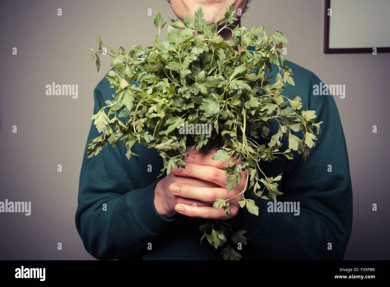 A happy young man is holding a big bunch of fresh parsley Stock Photo ...