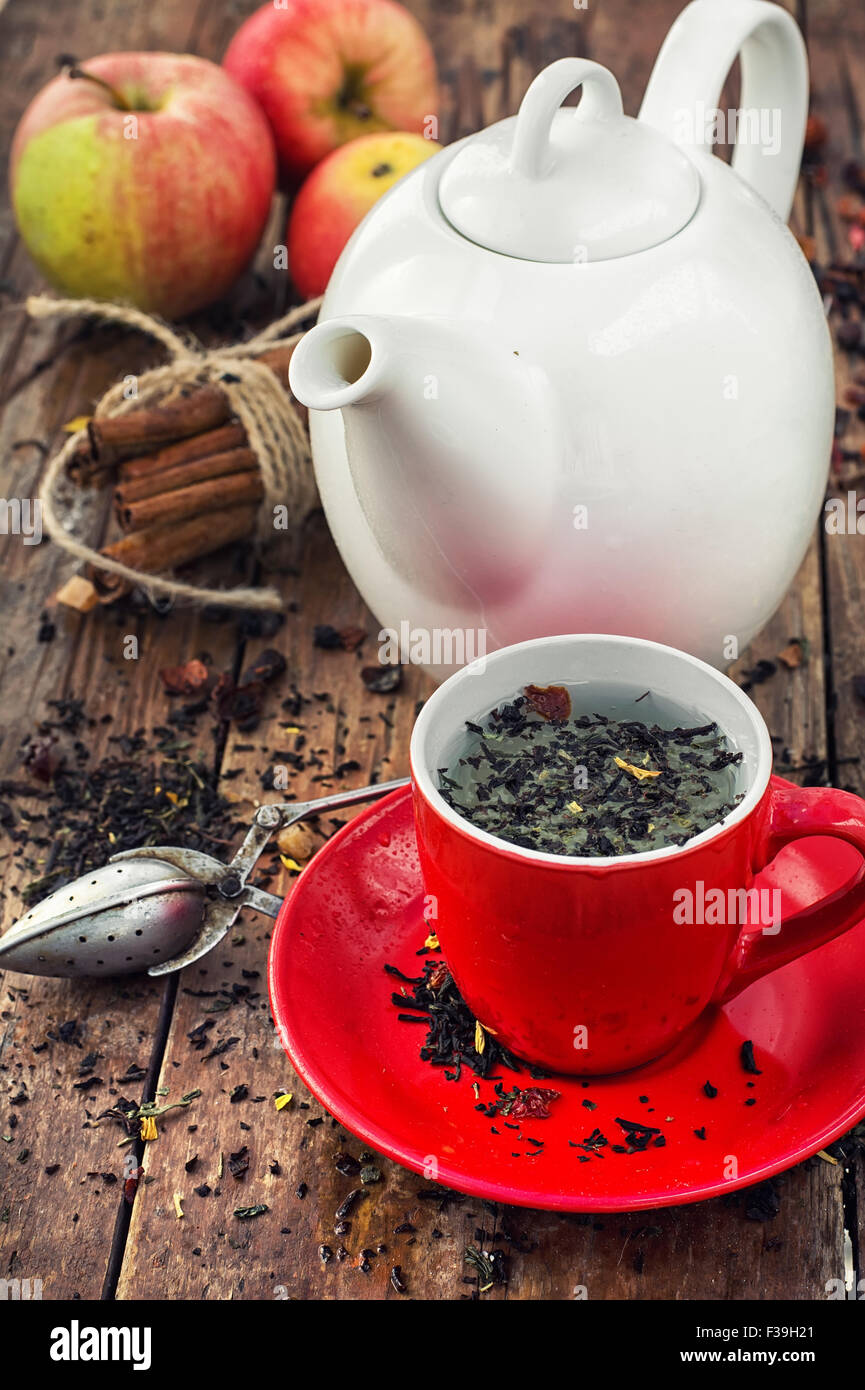White teapot and Cup with red Apple tea with cinnamon in a rustic style ...