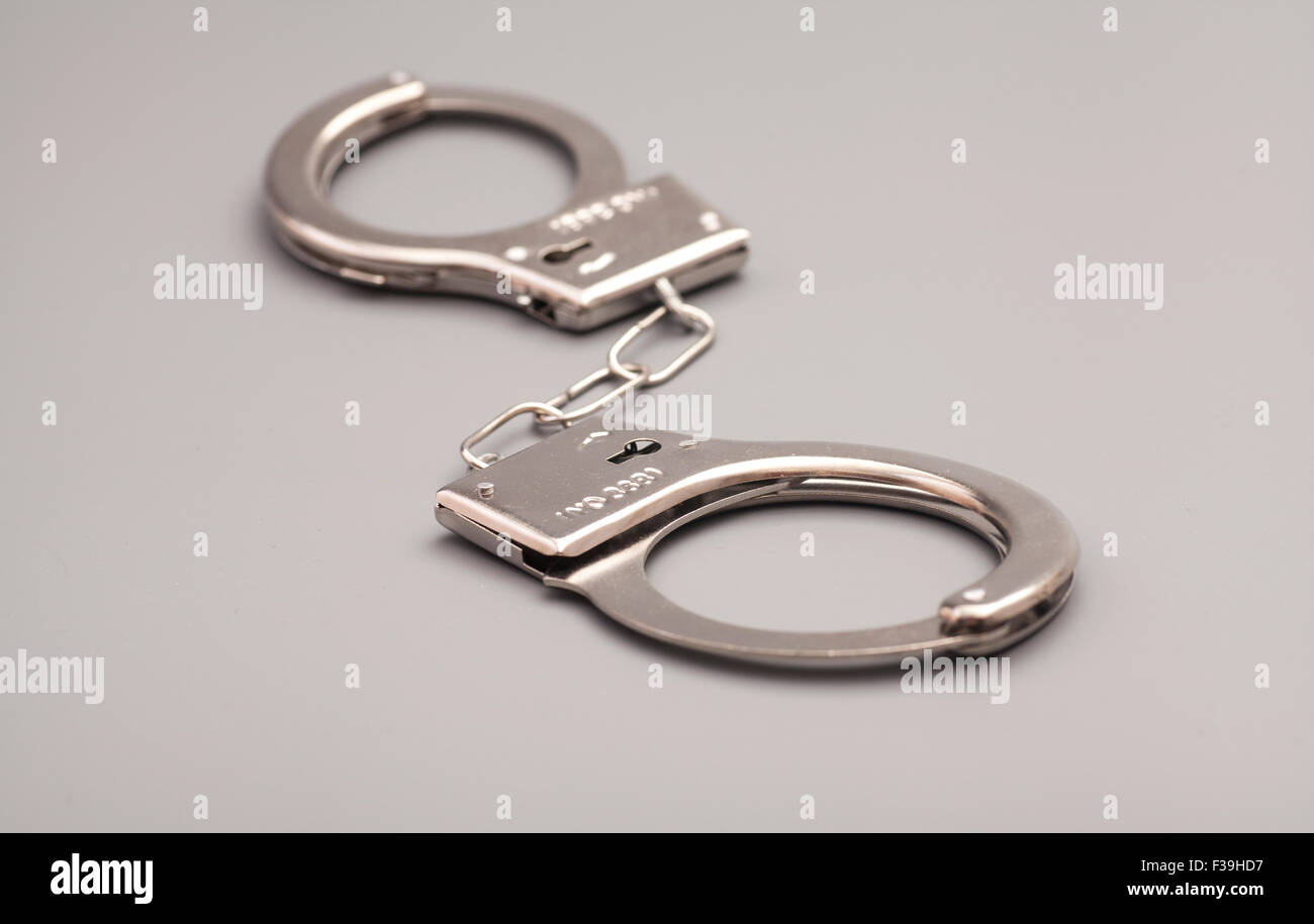 Handcuffs isolated on gray background Stock Photo - Alamy