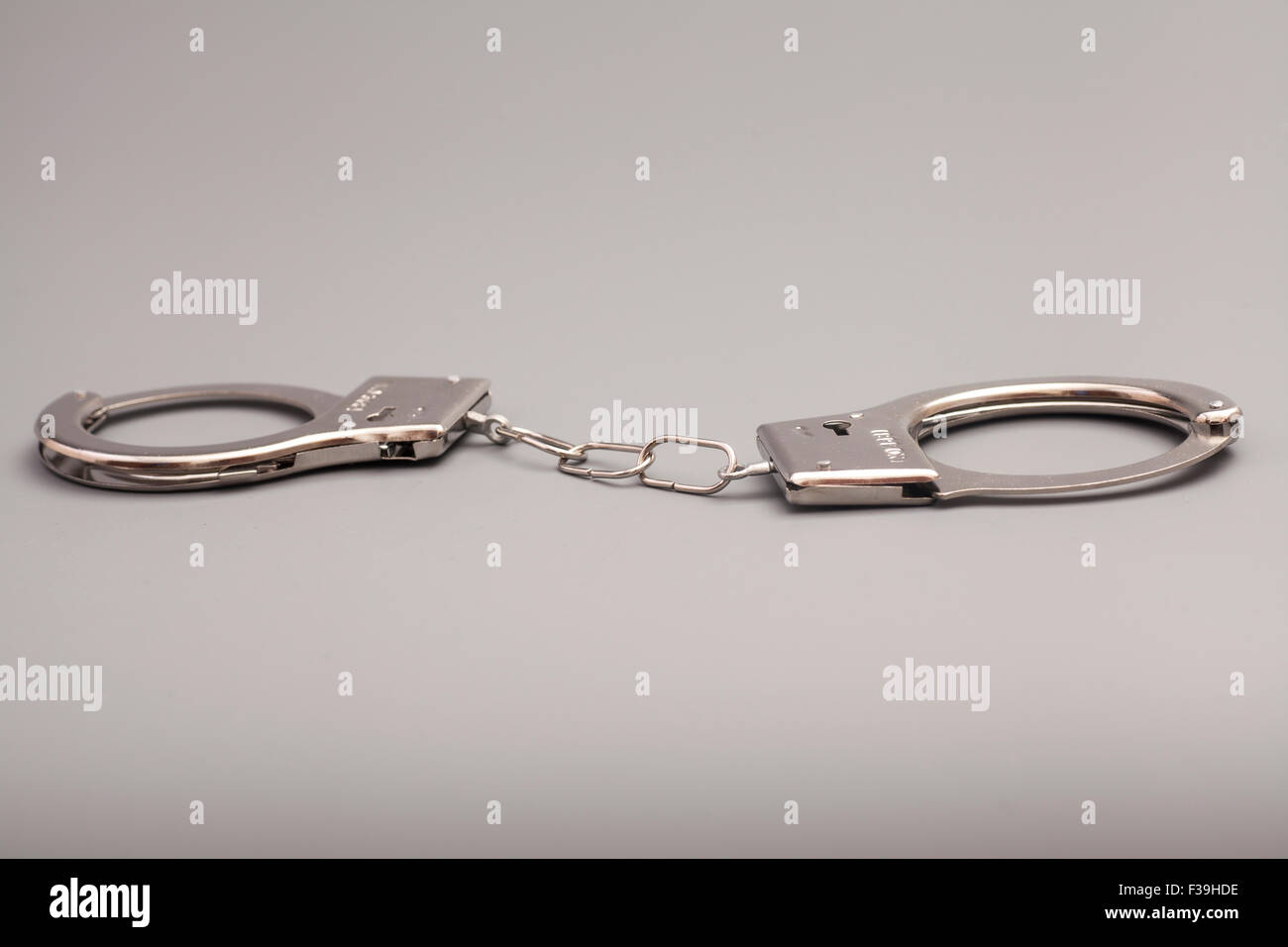 Handcuffs isolated on gray background Stock Photo - Alamy