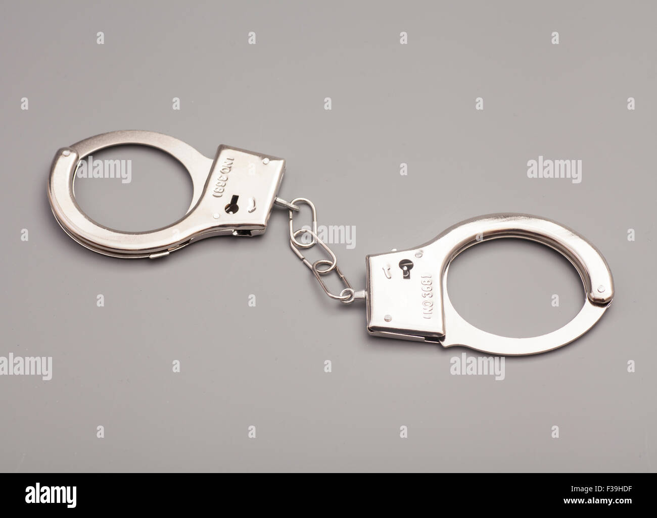 Handcuffs isolated on gray background Stock Photo - Alamy