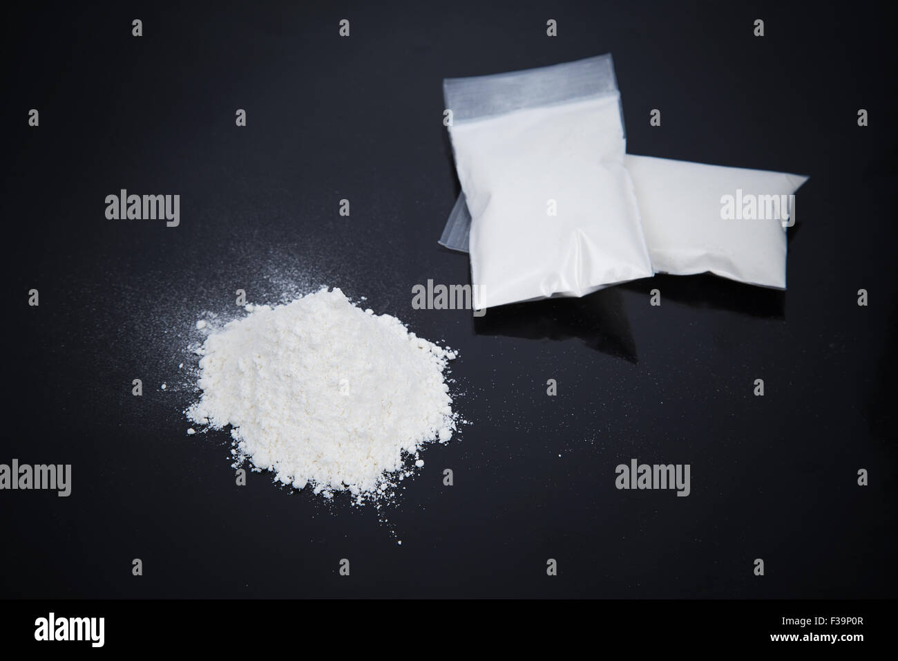 Transparent plastic bags with white powder isolated on black background ...