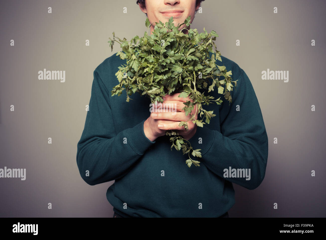 A happy young man is holding a big bunch of fresh parsley Stock Photo ...