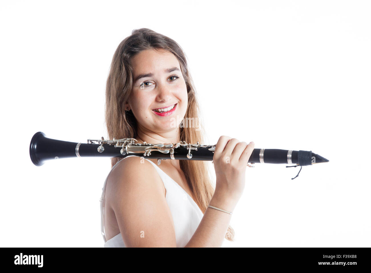 young brunette woman holds clarinet in studio on her shoulder and ...