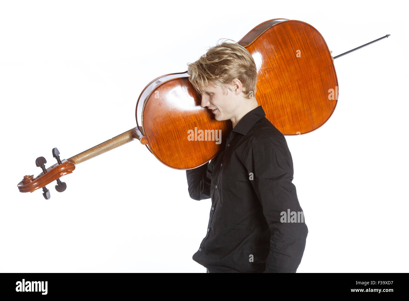 young blond caucasian man stands and carries cello on shoulder in ...