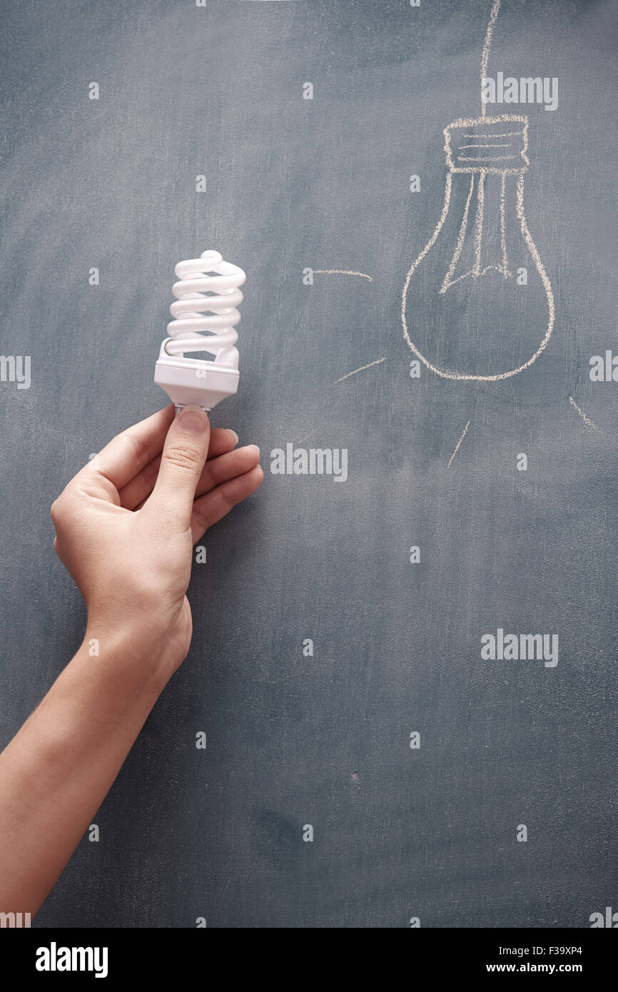 Human hand holding energy saving lamp at the blackboard Stock Photo - Alamy