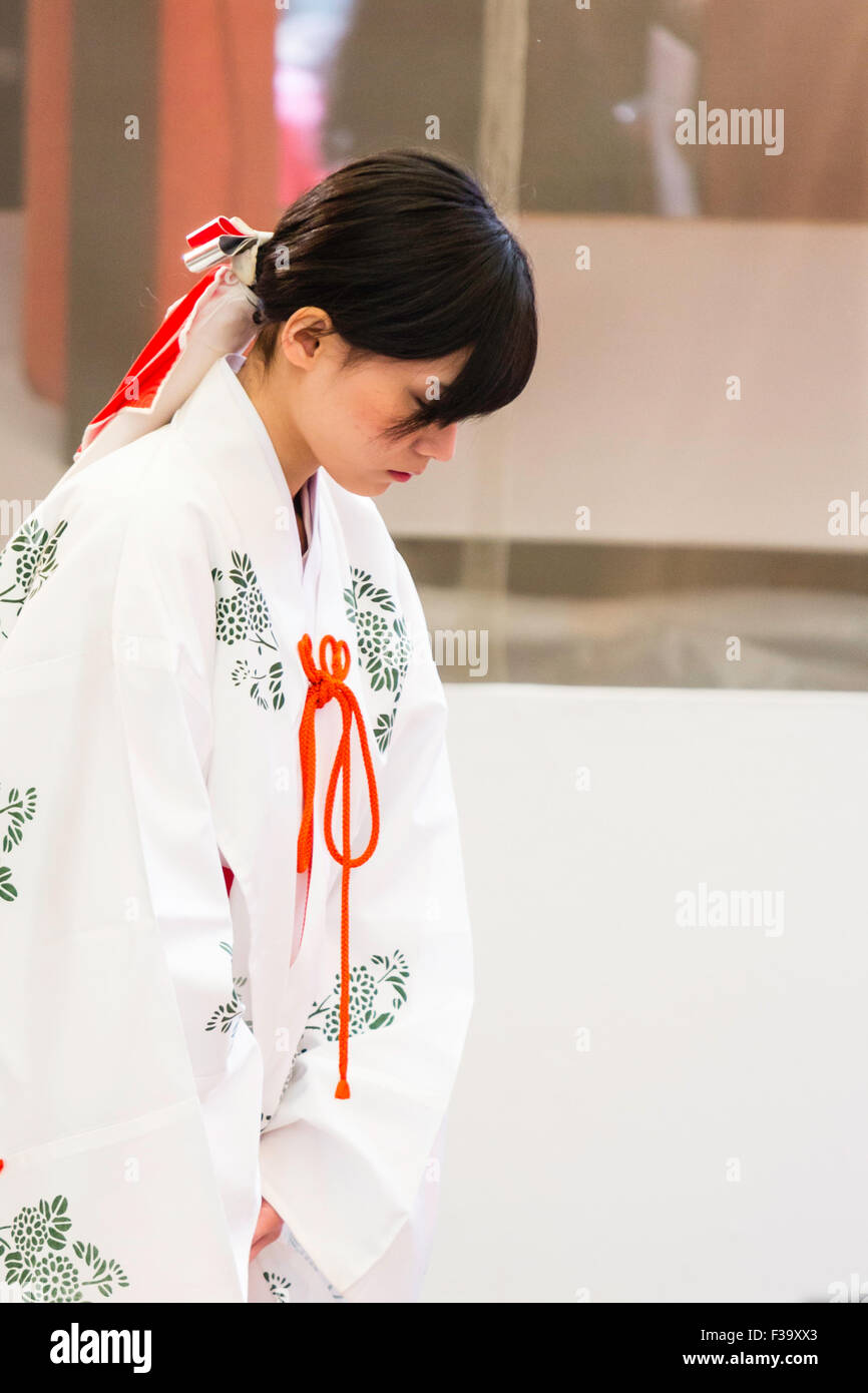 At the Ikuta Shinto Shrine in Kobe, a young Miko, shrine maiden, bows ...