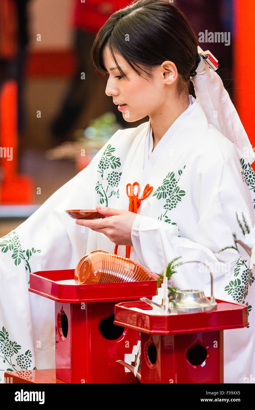 Shinto shrine Maiden, Miko, handing out gifts, offerings, to paying ...