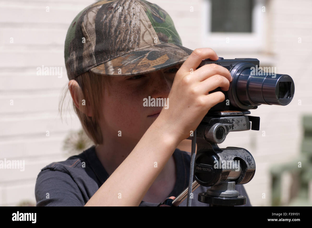 Boy using camera on tripod Stock Photo - Alamy