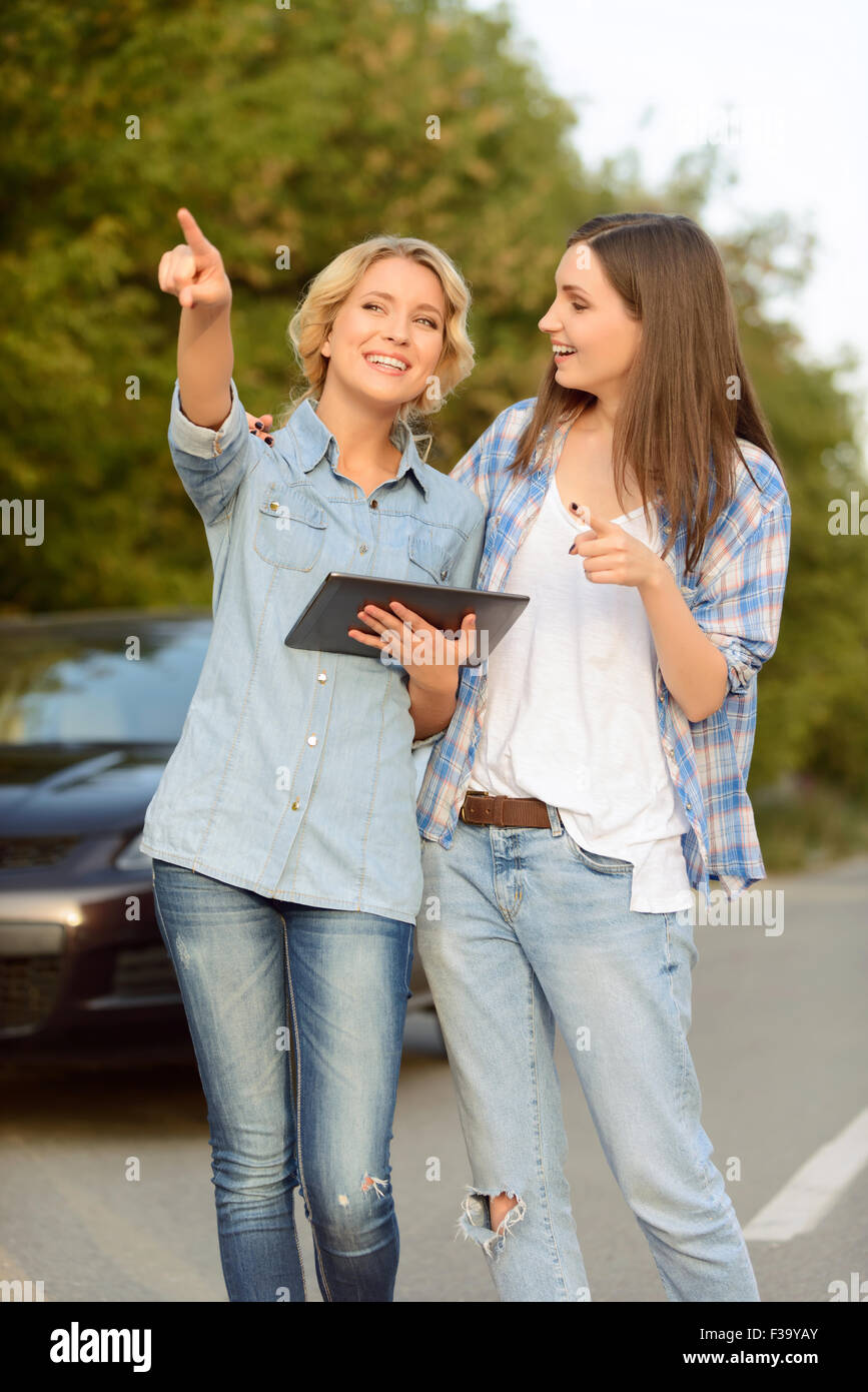 What is it. Overjoyed delighted charming young friends pointing up and ...