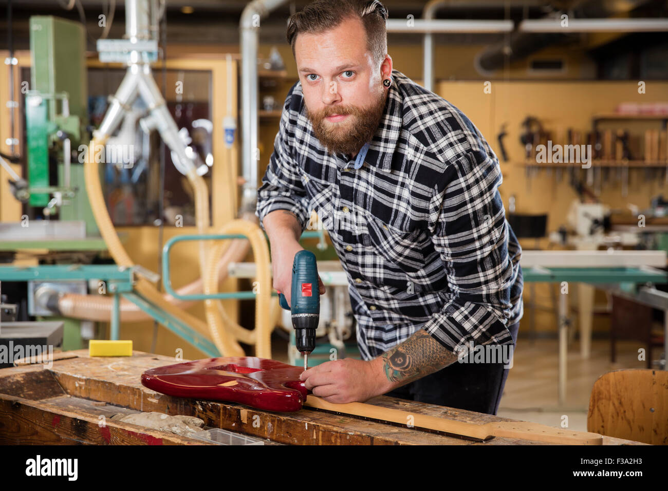 Young adult craftsman who works with a guitar in a workshop for wood ...
