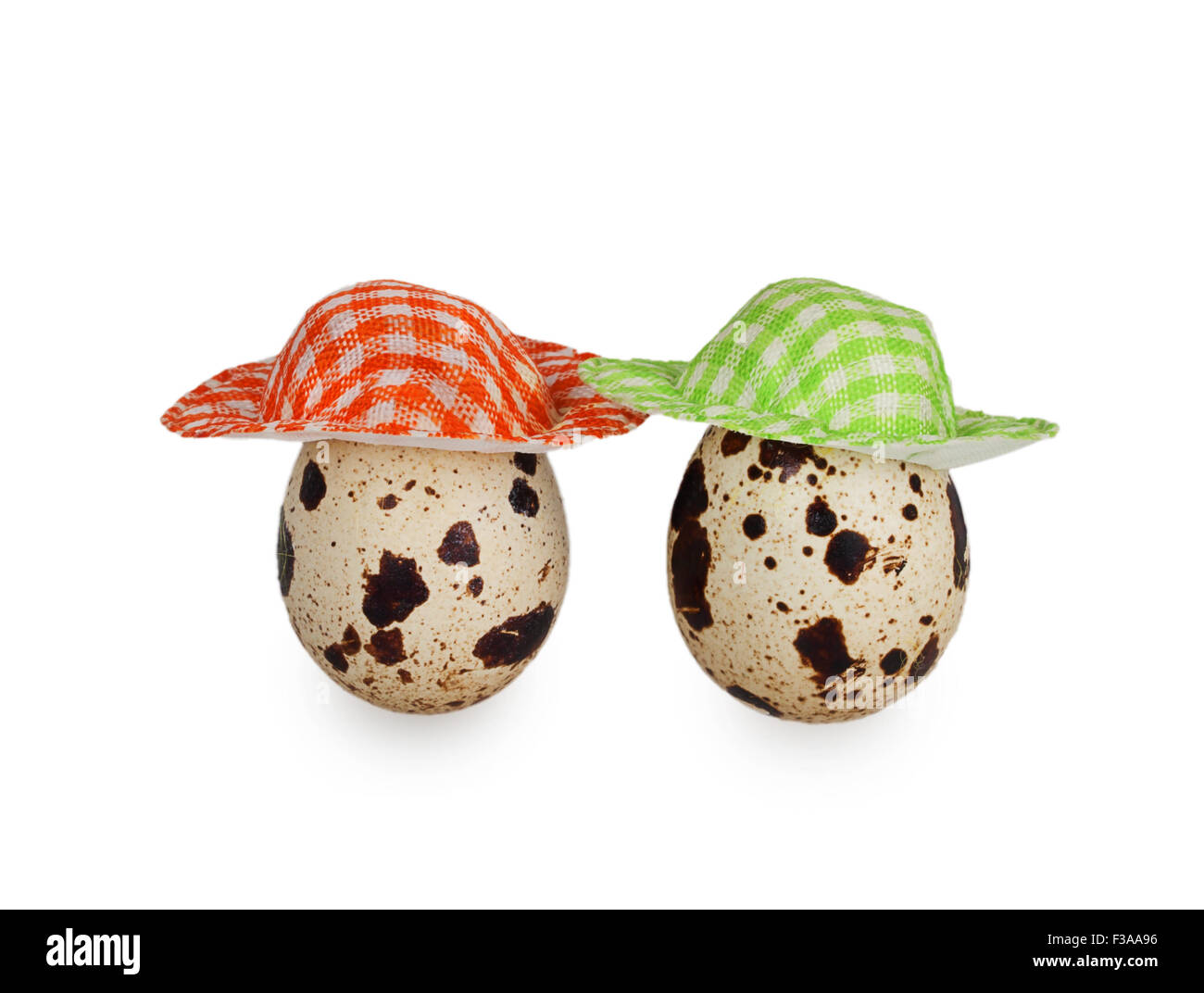 two quail eggs dressed in colorful hats isolated on white background ...