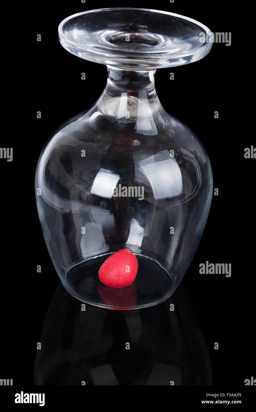 red small stone under an inverted glass isolated on a black background ...
