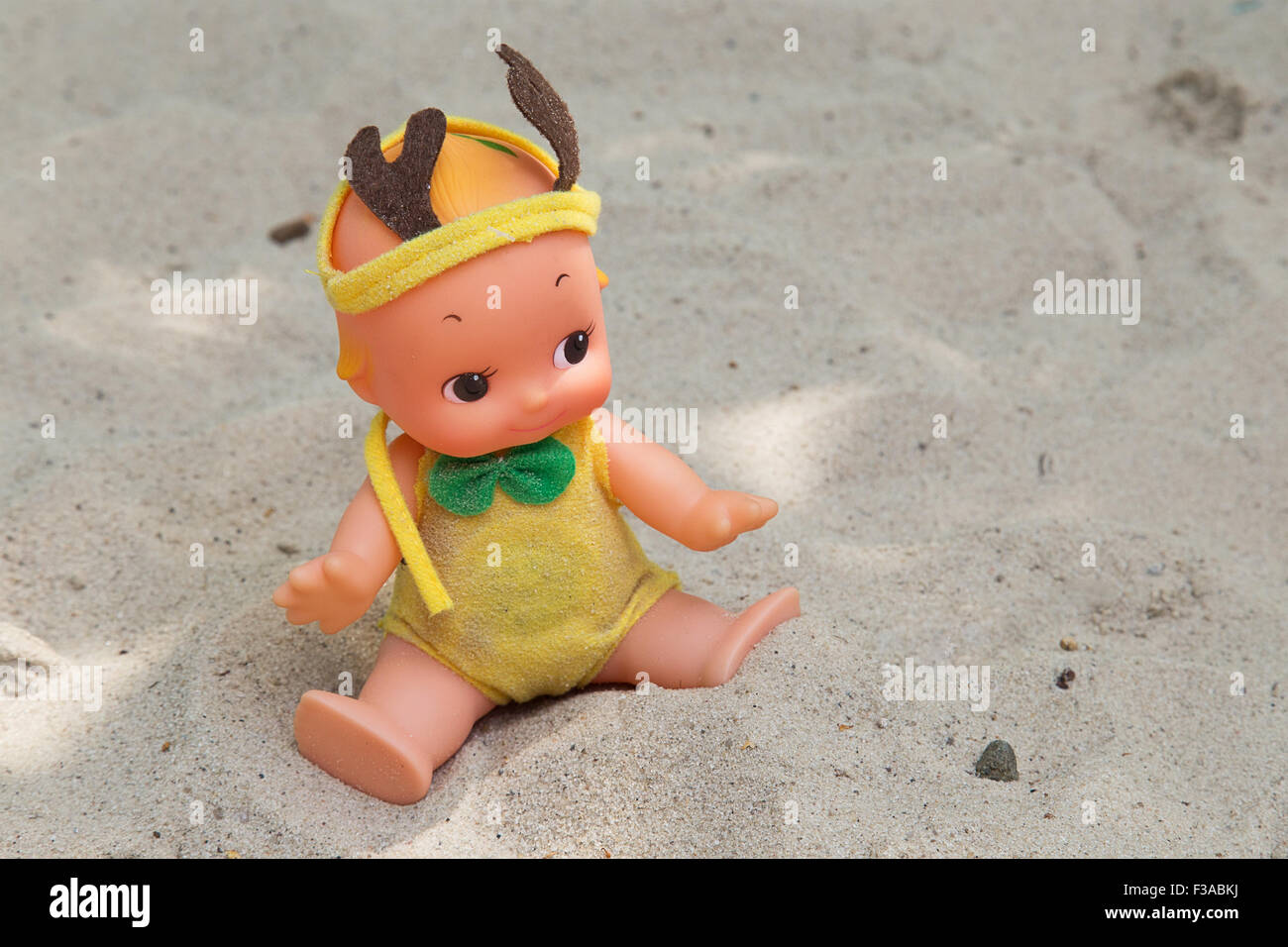 Doll in a yellow dress sitting in the sand Stock Photo - Alamy