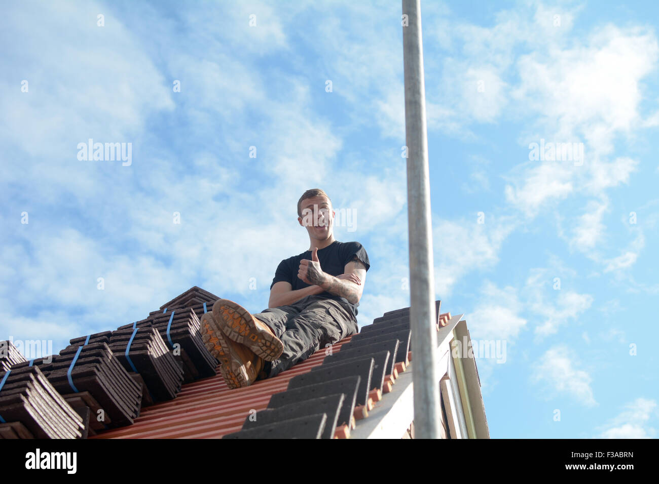 Roofer taking a break whilst fitting roof tiles on house in Bedford ...