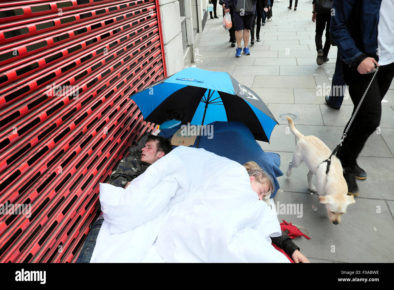 Two young homeless people person couple sleeping rough on the pavement ...