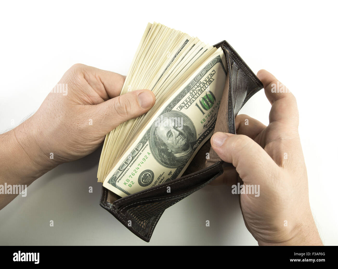 Hand opening a wallet containing 100 US dollar banknotes, studio shot ...