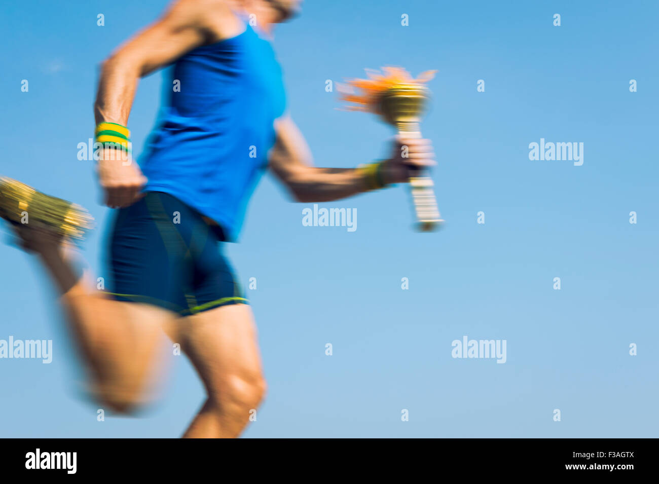 Torchbearer athlete in blue running with sport torch in motion blur ...