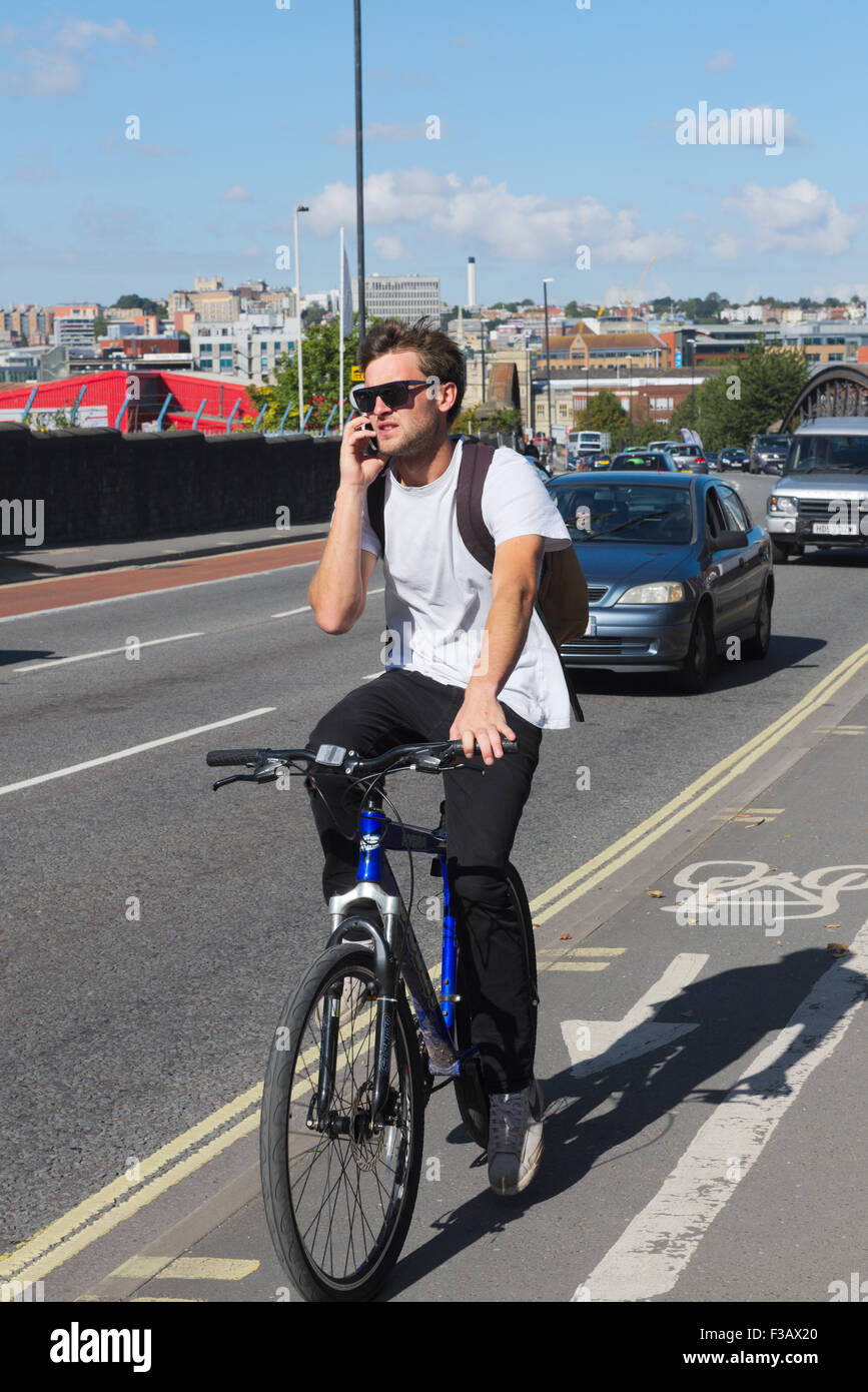 Cyclist talking on mobile phone while cycling along street Stock Photo ...