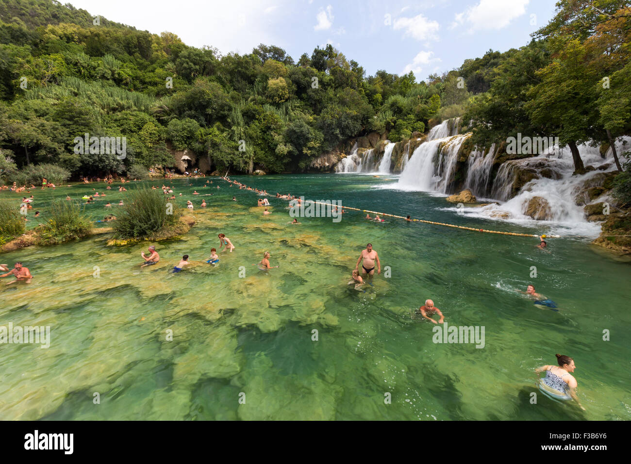 People swimming at a lake in front of waterfalls at the Krka National ...