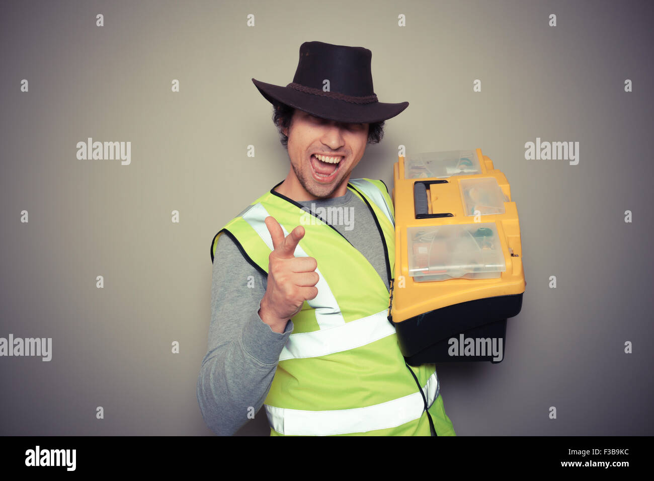 A cowboy builder with a big tool box is pulling silly faces and ...