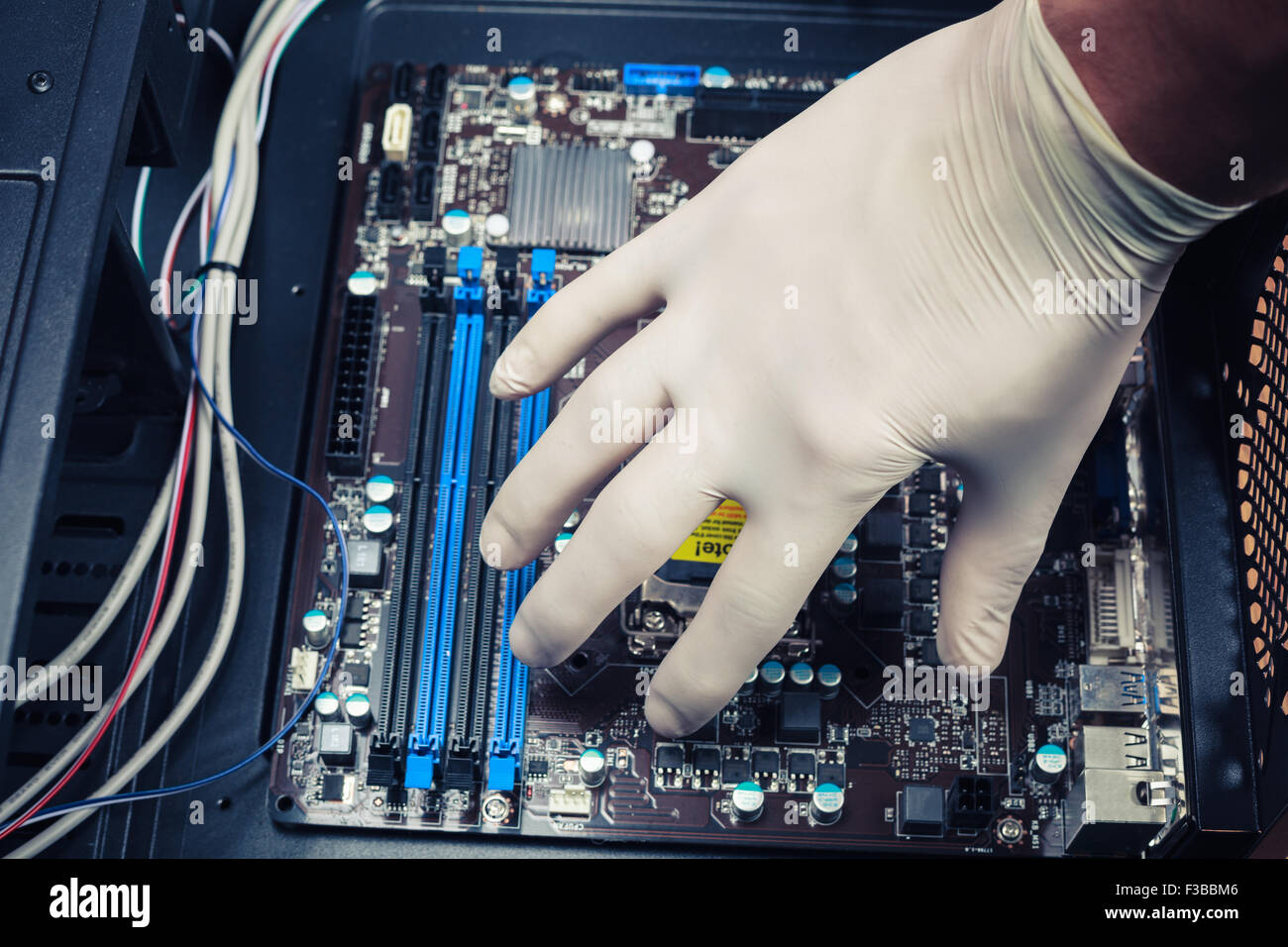 A hand wearing a rubber glove is installing computer components Stock ...