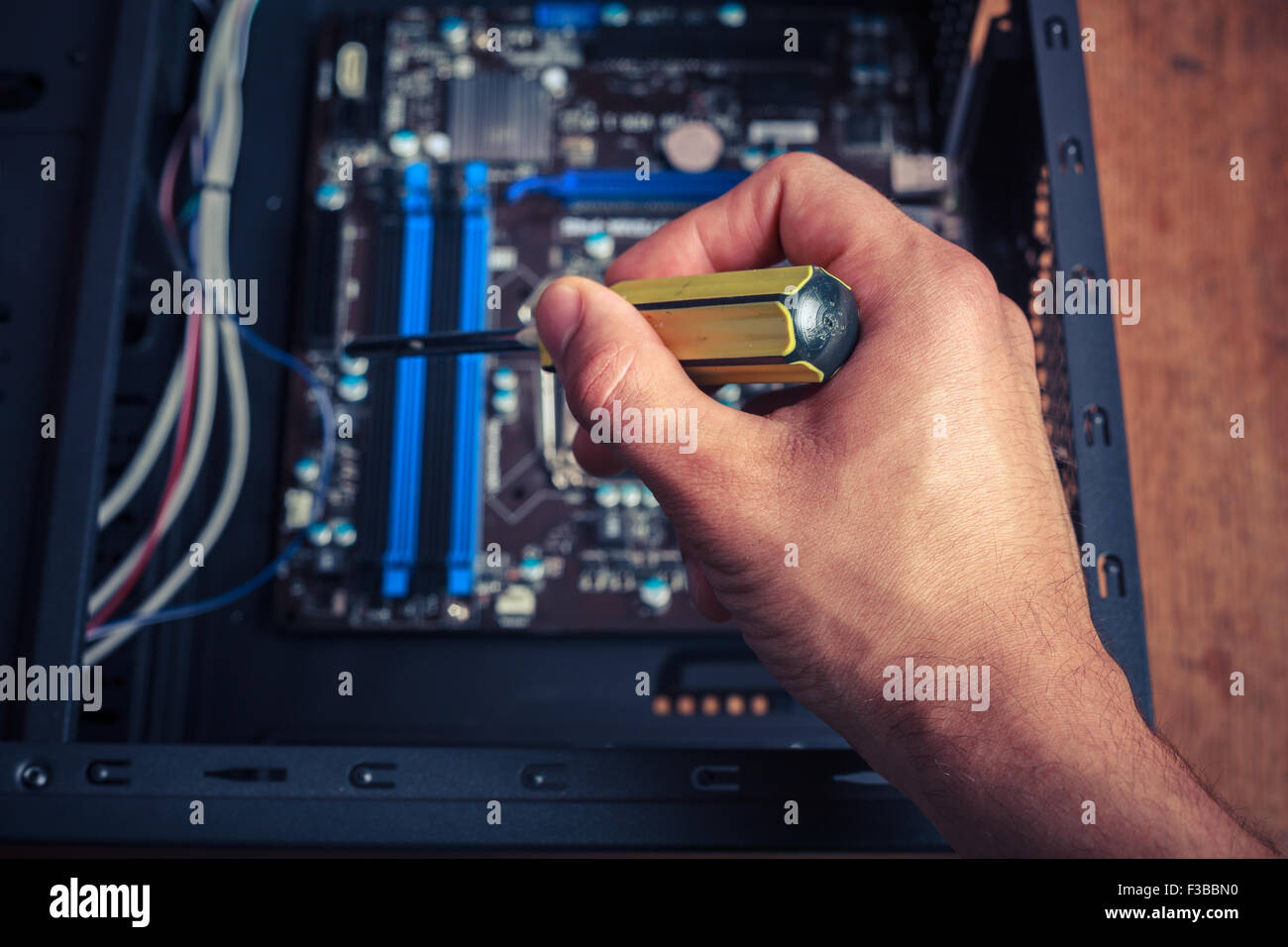 A hand holding a screwdriver is installing or repairing computer ...